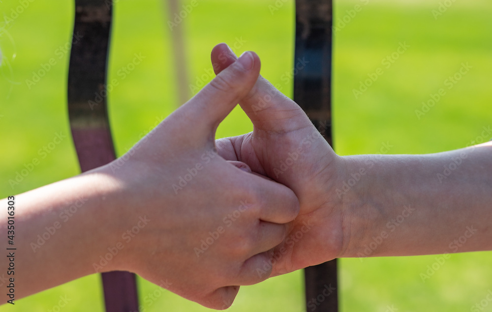 Two children playing a thumb war battle with the objective to pin the ...