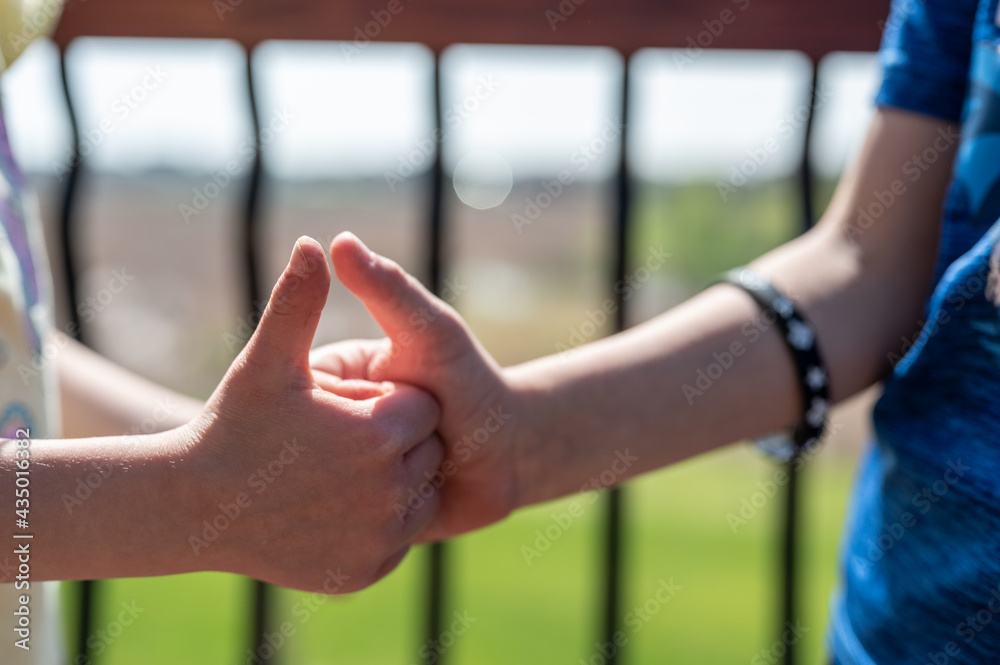 Two children playing a thumb war battle with the objective to pin the ...