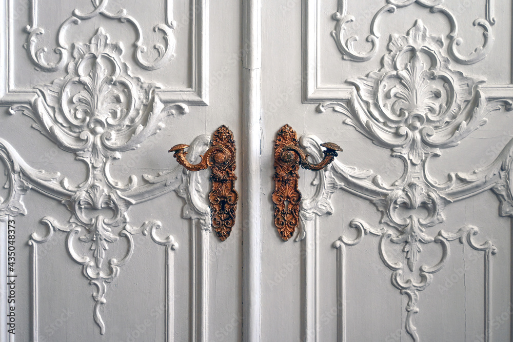 An old wooden door with brass handles and architectural decor. Wood ...