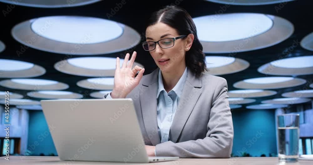 Beautiful female TV presenter with glasses sits at table in news studio ...