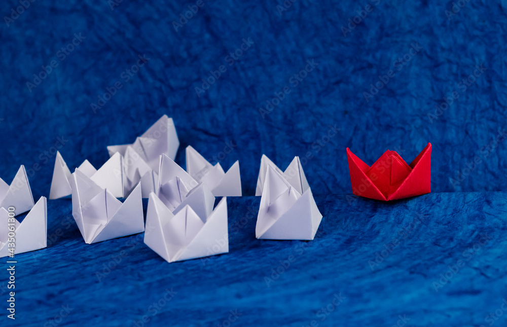 Leadership concept shown using white paper boats wandering in the sea ...