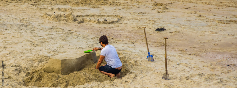 Adult male sculpting a sand castle on the beach, fun and creative ...