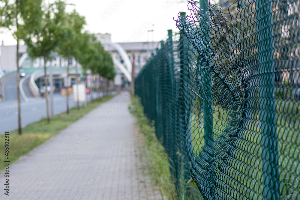 Green damaged wire-mesh fence is ruined after collision with car ...
