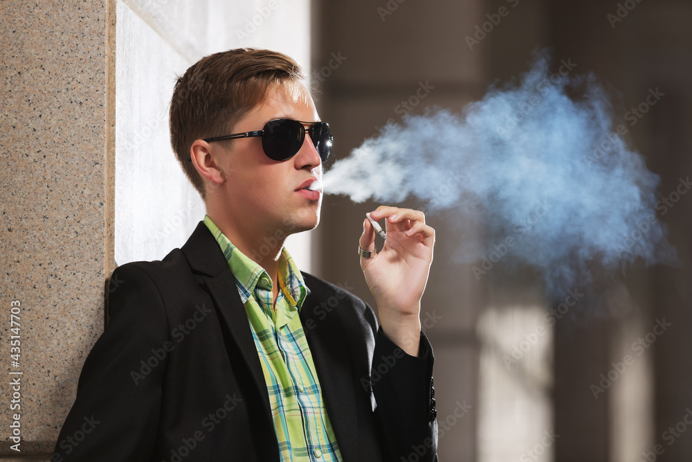 Young man in black blazer and sunglasses smoking a cigarette Stock ...