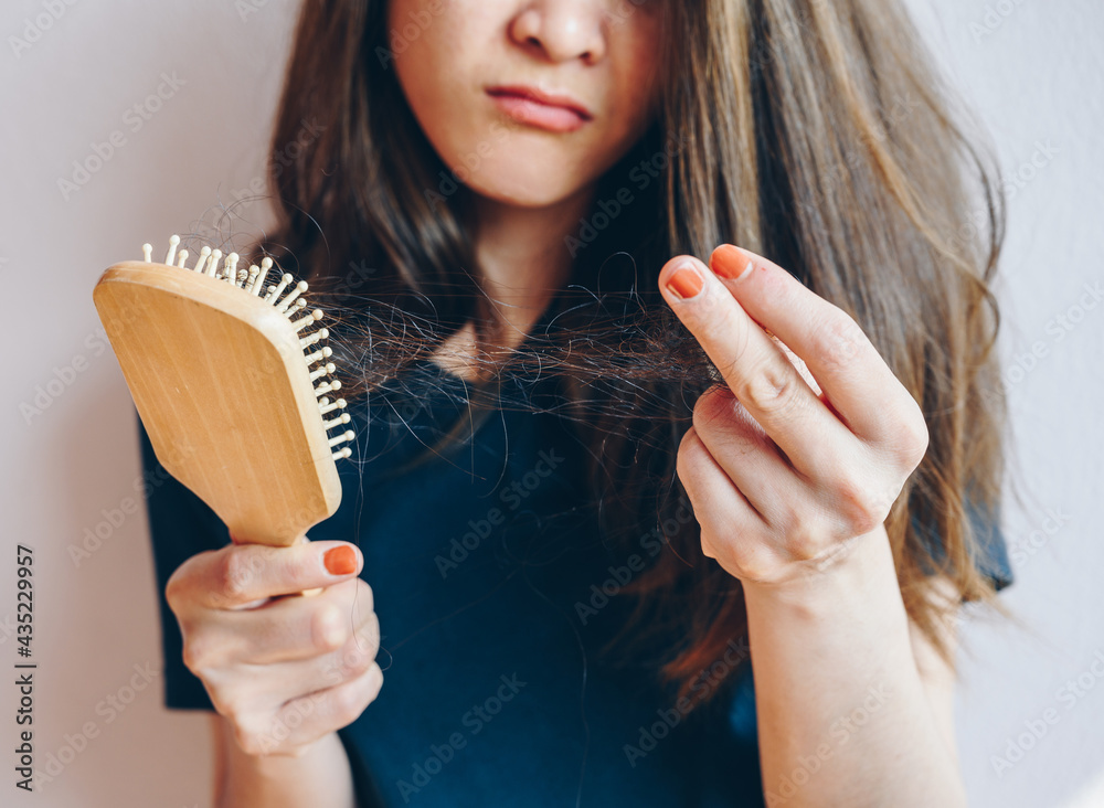 Cropped shot of worried woman holding comb with hair loss after ...