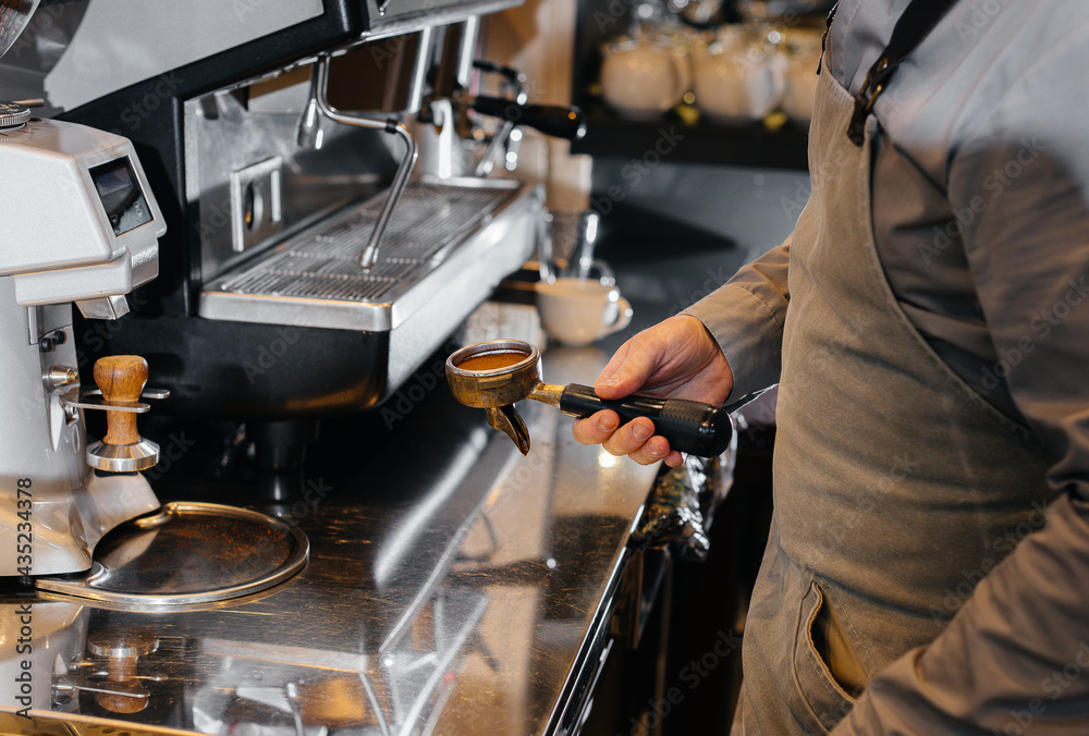 Close-up of a masked barista preparing a delicious coffee at the bar in ...