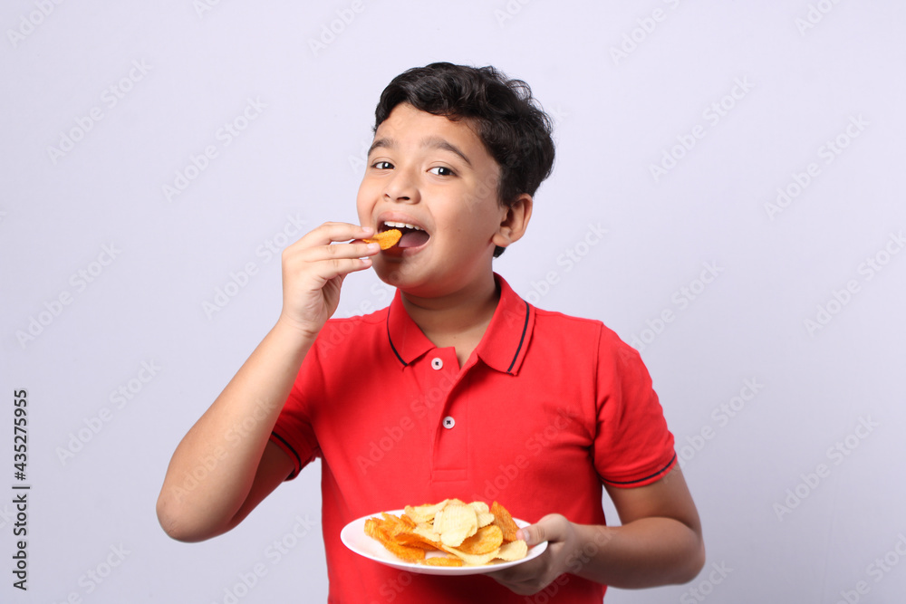 Indian Kid or boy eating potato chips or wafers. Stock Photo | Adobe Stock