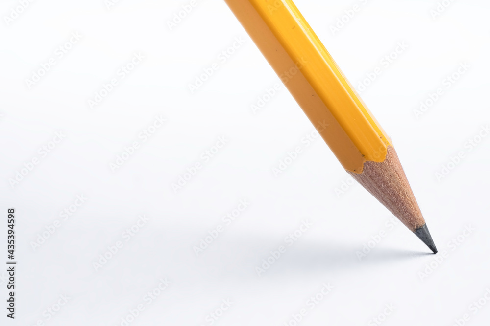 Pencil with shadow stands on white paper. The sharp point has just been ...