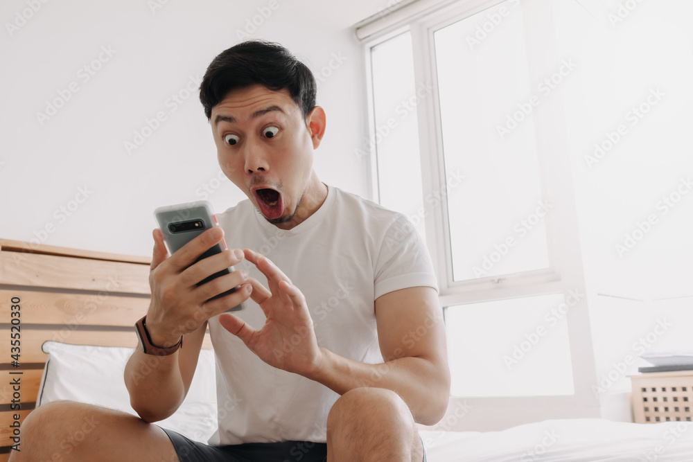 Wow face of Asian man surprised while look at the s'martphone in his ...