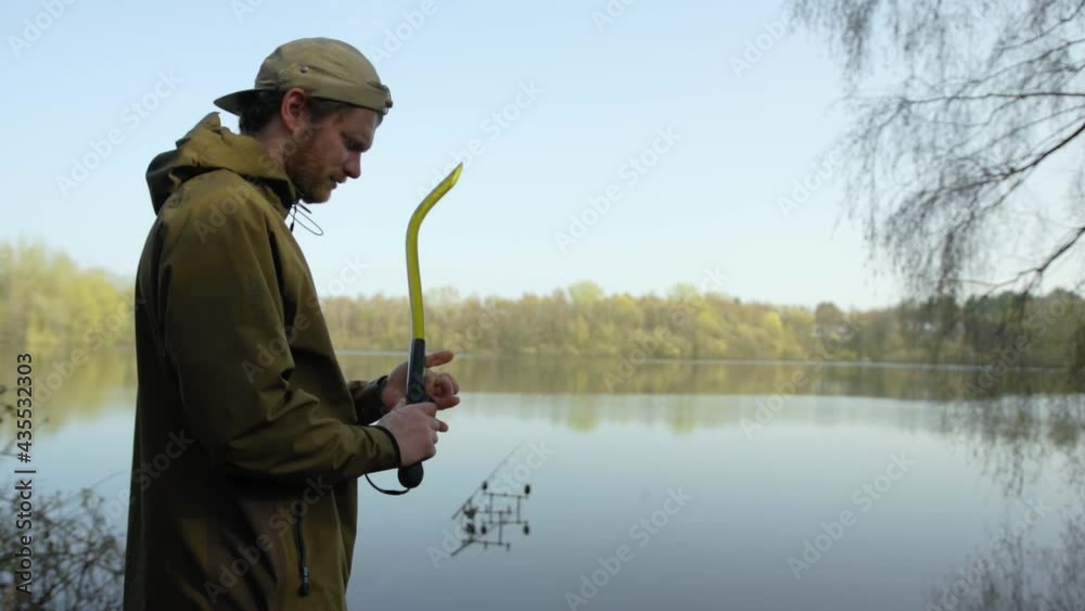 Fisherman baiting carp lake. Young caucasian male using bait thrower to ...