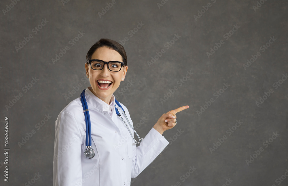 Funny crazy emotional female doctor standing on gray background smiling ...