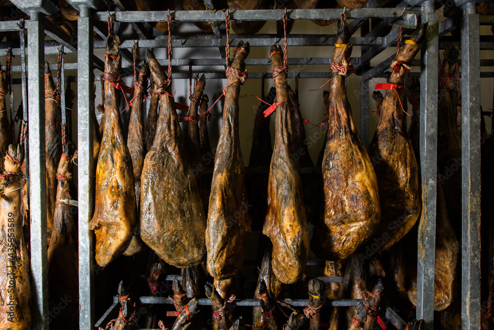many Iberian Pata Negra hams hung ready to be sold. Jamon serrano. A ...