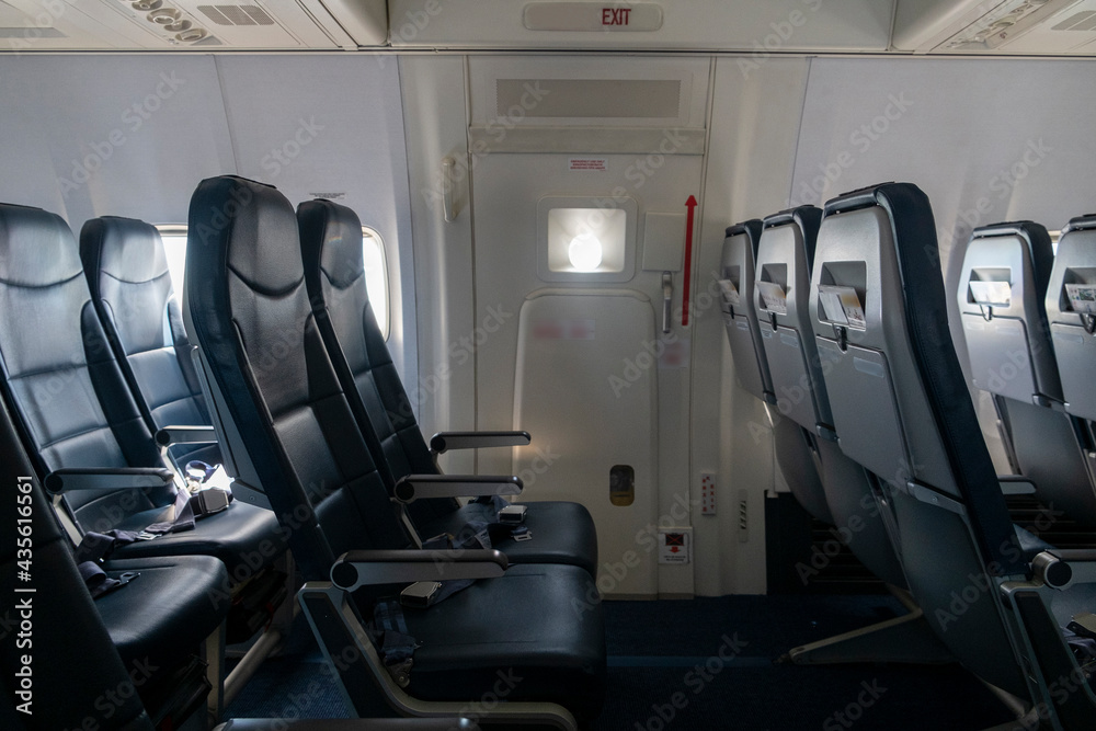 Rows of black leather seats and porthole windows in commercial aircraft ...