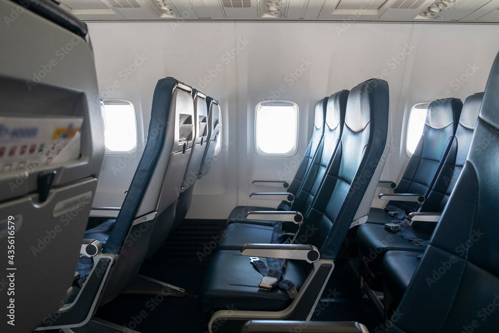 Rows of black leather seats and porthole windows in commercial aircraft ...