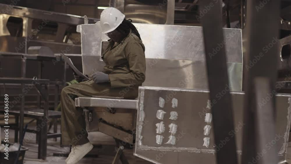 Full shot of female African dockyard worker wearing green overalls ...