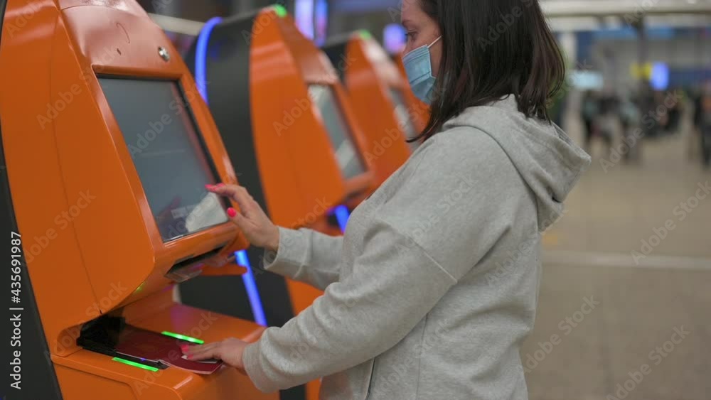 woman using self check-in machine in the airport. woman checks in on ...