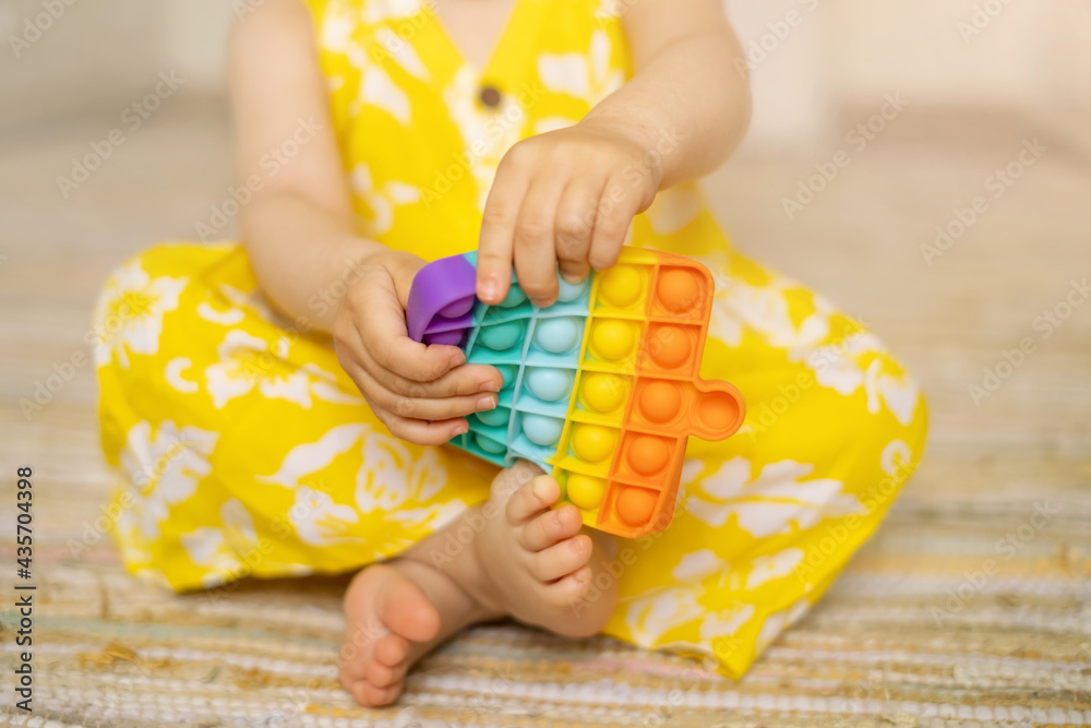 A little girl is playing with a modern pop it toy. A fascinating ...