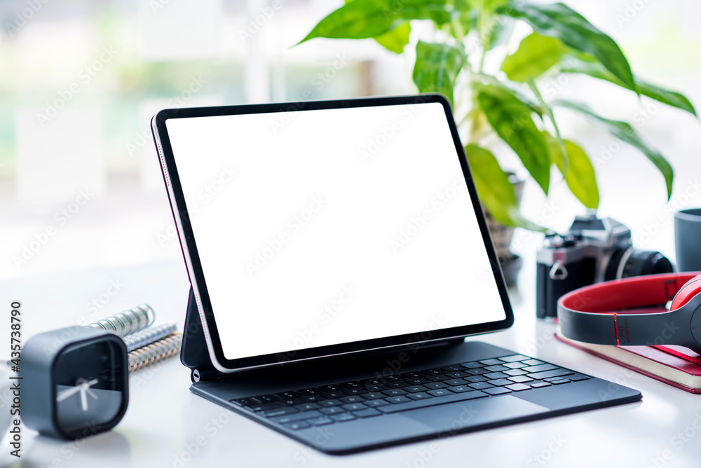Tablet blank white screen with devices placed on the office table. Mock ...