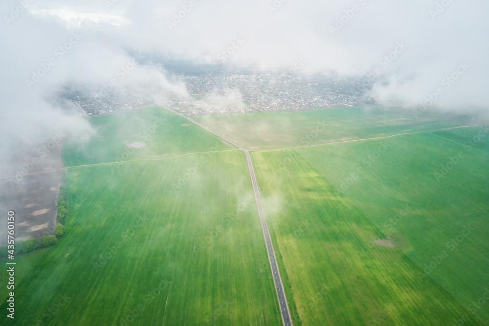 Flight through the clouds. Aerial view of green field with fluffy ...