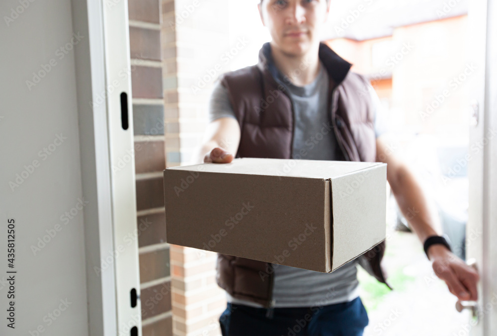 Deliveryman gives the carton box to the customer at the door of his ...