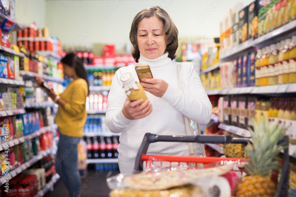 Elderly shopper using smartphone scans qr code on label in grocery ...