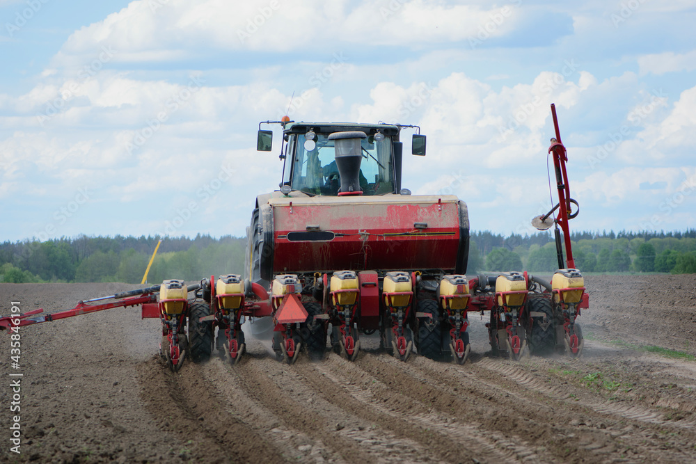 red tractor in a field rear view, tractor planting crops on an ...