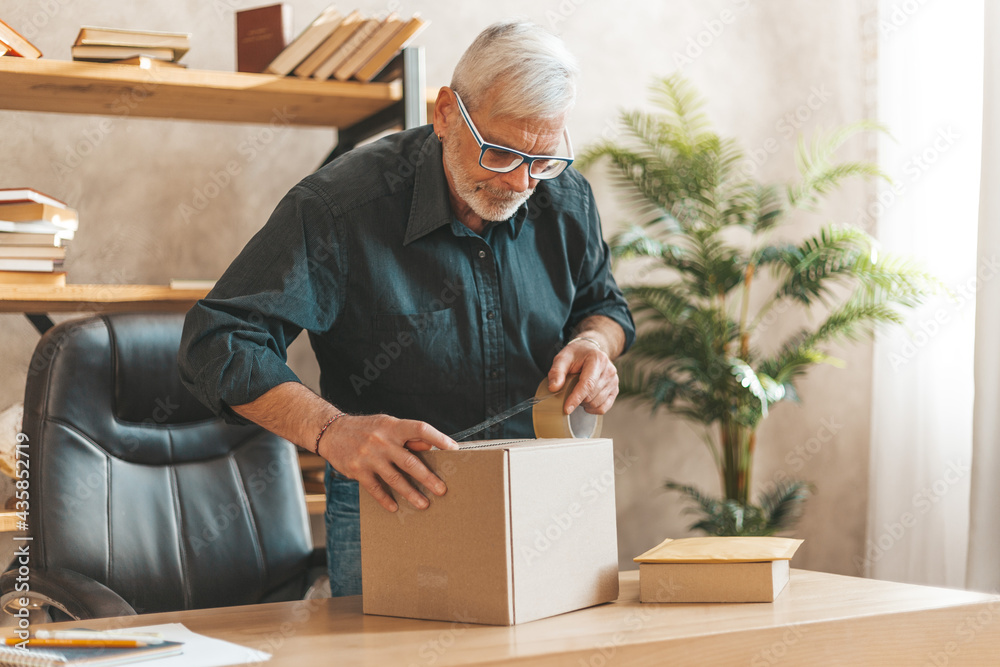Send a parcel. Mature man packing cardboard box in the office. Delivery ...