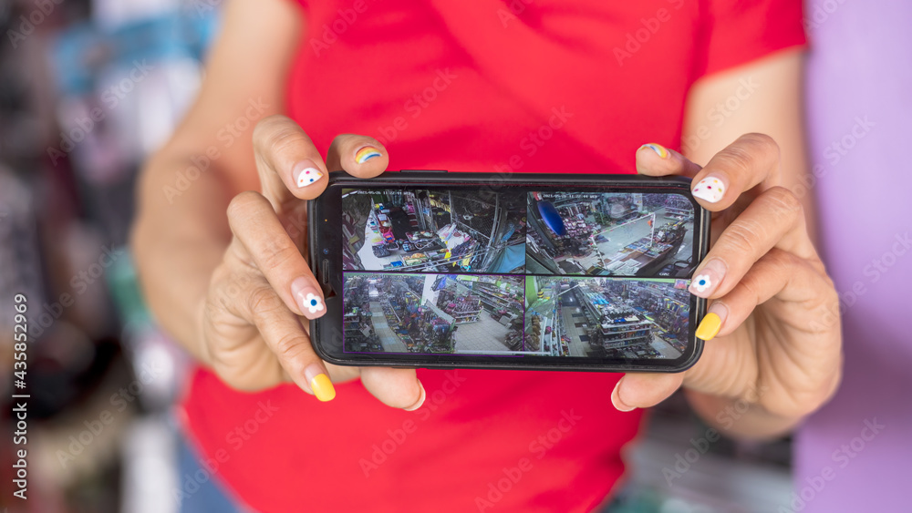 Hand holding a mobile phone extended to see the video checking the CCTV ...