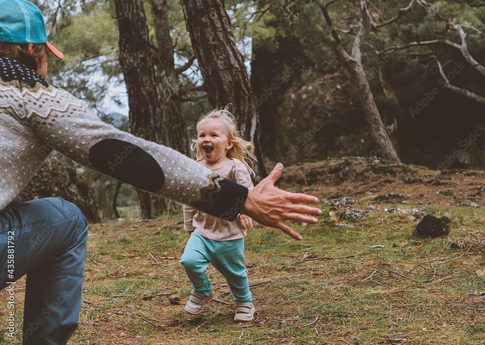 Laughing child running to father family walking together in forest ...