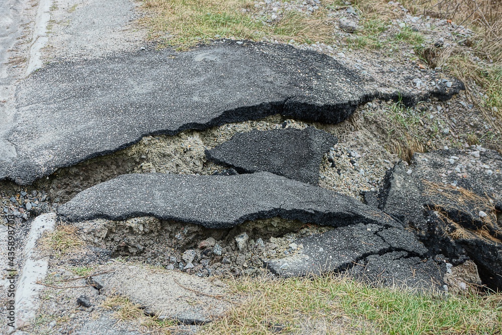 destroyed road made of pieces of black asphalt in gray earth overgrown ...