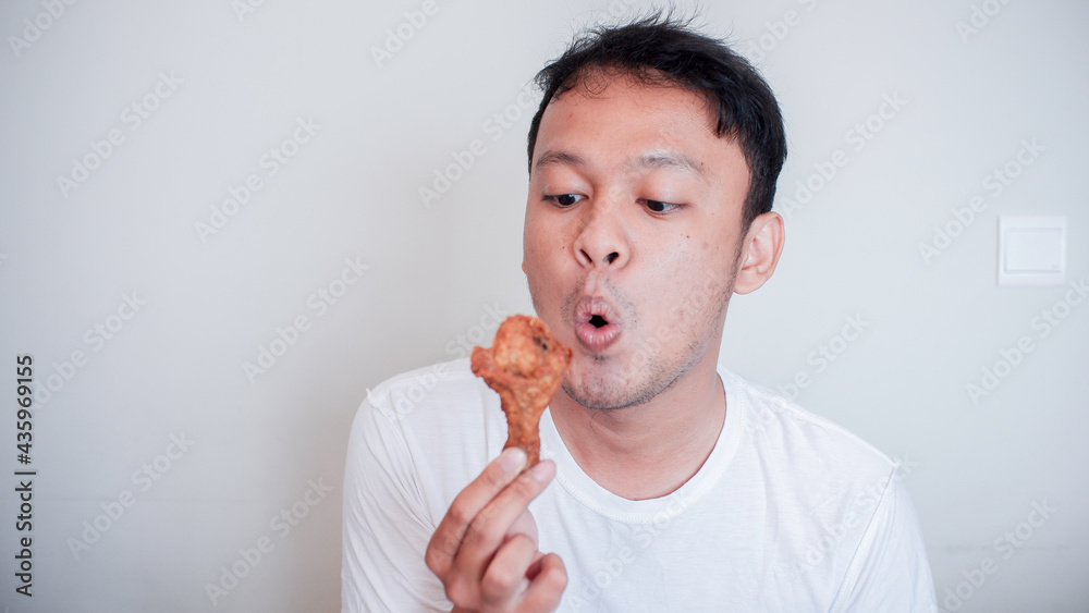 Shock and Wow face of Young Asian man is eating fried chicken wear ...