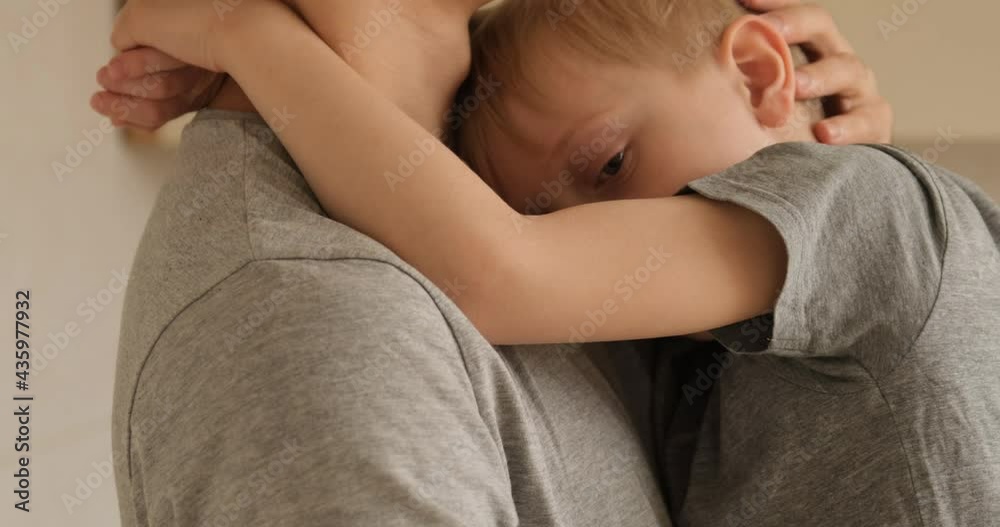 Father soothes a sad child. Boy in his father's arms hugs him by the neck. Father strokes child ...