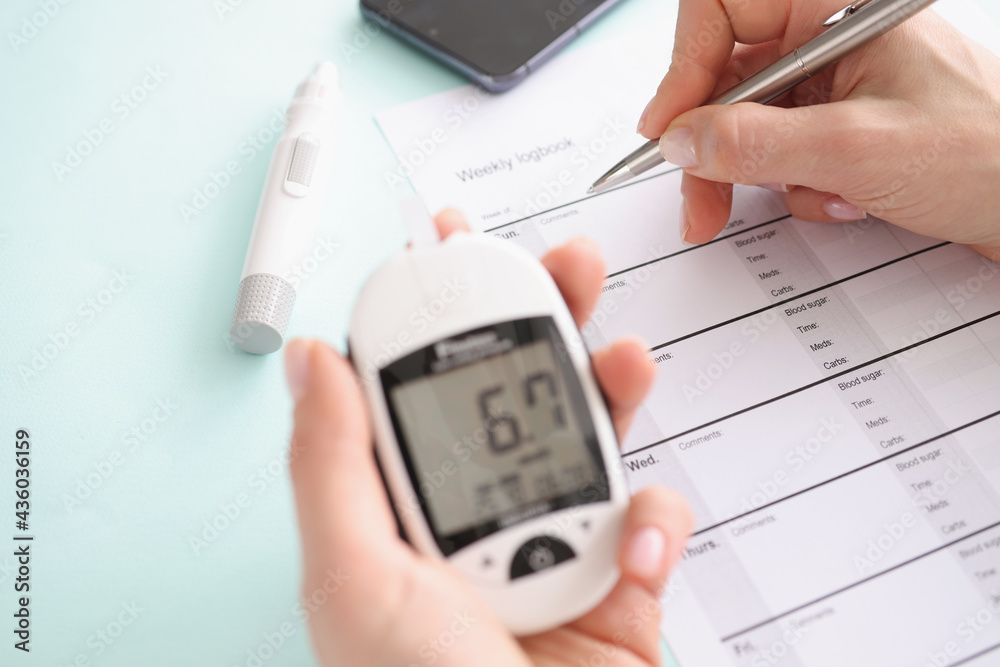 Glucometer with blood test results in patient hand fills in results in ...