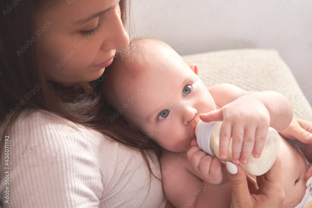Foto de Mom feeds her happy child son baby milk powder, baby bottle do ...