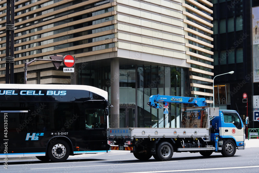 TOKYO, JAPAN - May 01, 2021: Hydrogen fuel cell bus and a crane truck ...