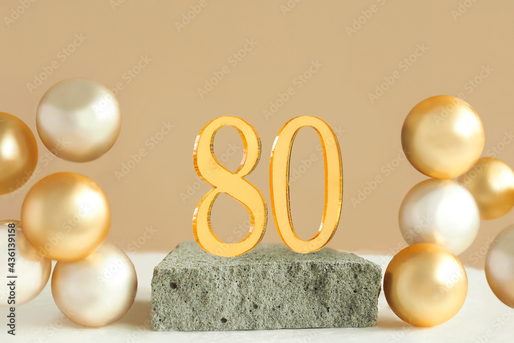 Number 80 on a concrete podium and volumetric golden balls on a beige ...
