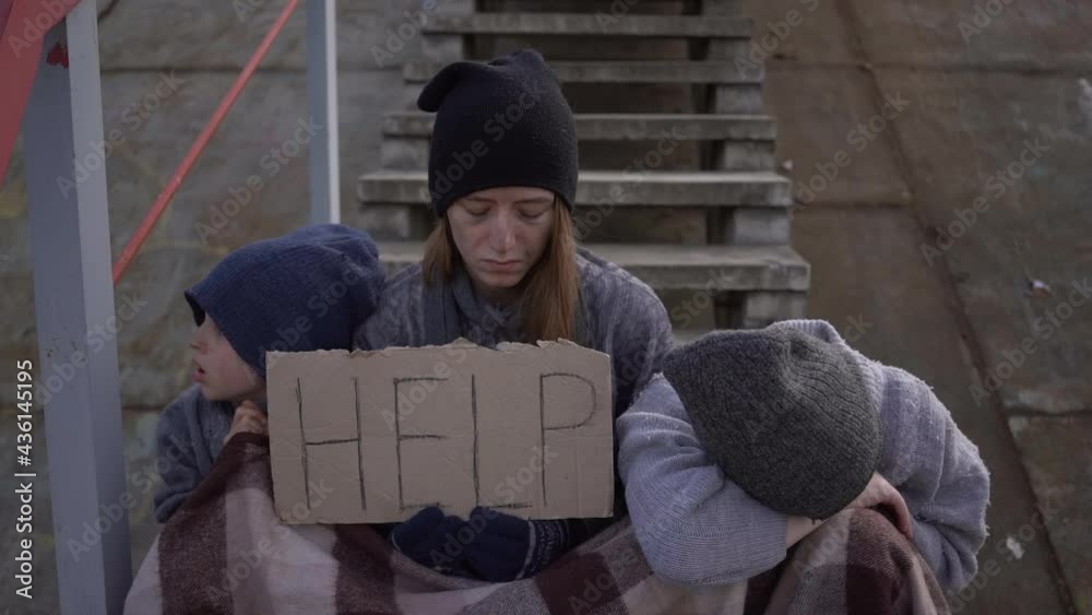 homeless mother with children with a sign Help on the stairs in an ...