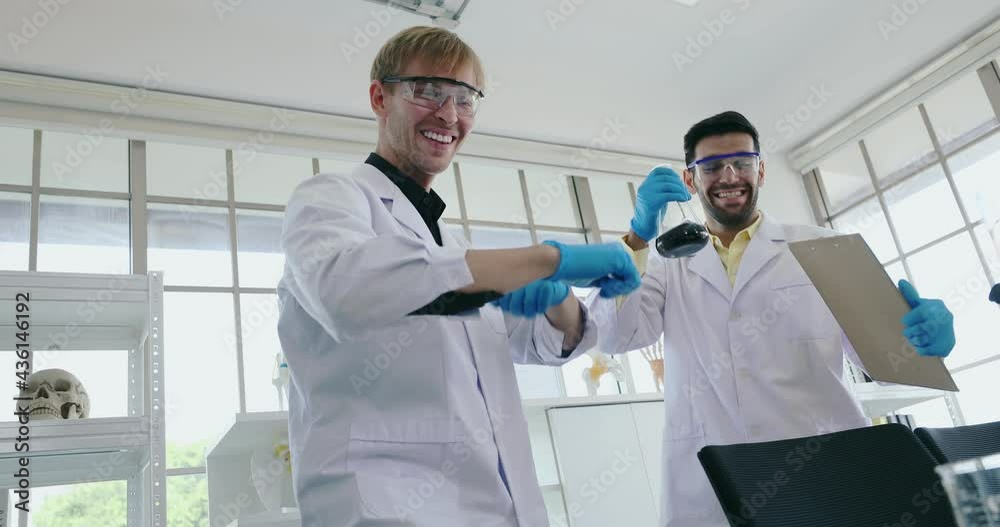 two young funny male scientists wearing white lab coat dance around in ...