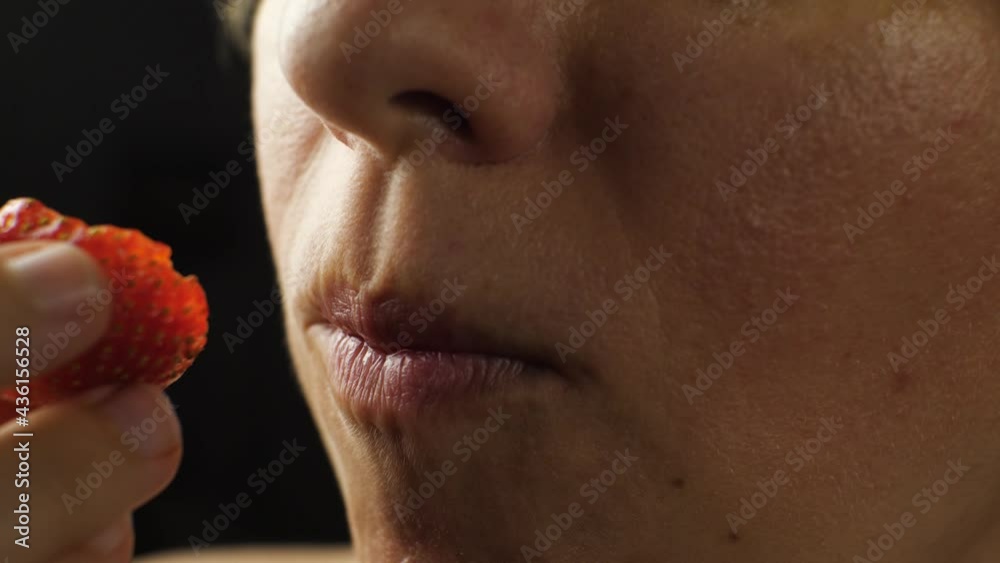 Close-up of a woman biting a strawberry. The juice from the berry ...