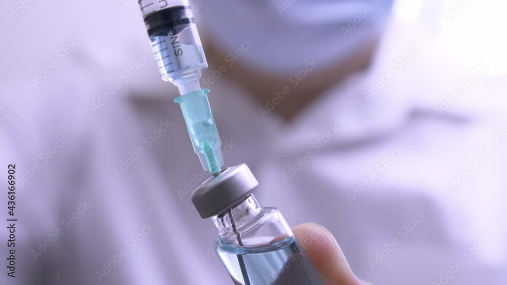Medical hands and syringes and a blue vaccine bottle at the hospital ...