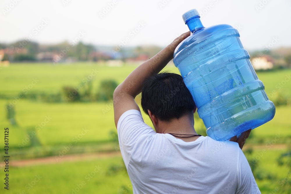 Man carrying a bottle of drinking water on his shoulder to service the ...