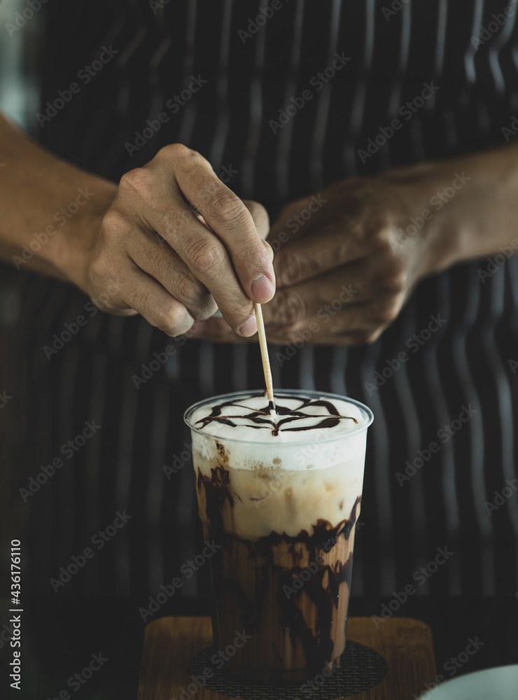 Unrecognizable barista carefully decorating creamy foam of iced coffee ...