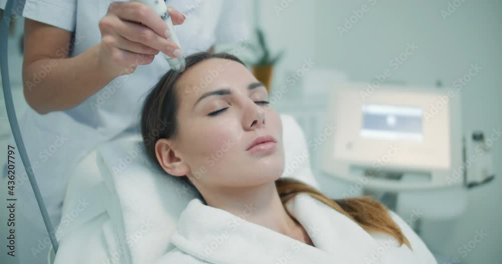 Close up a female client is sitting with closed eyes while having a non ...