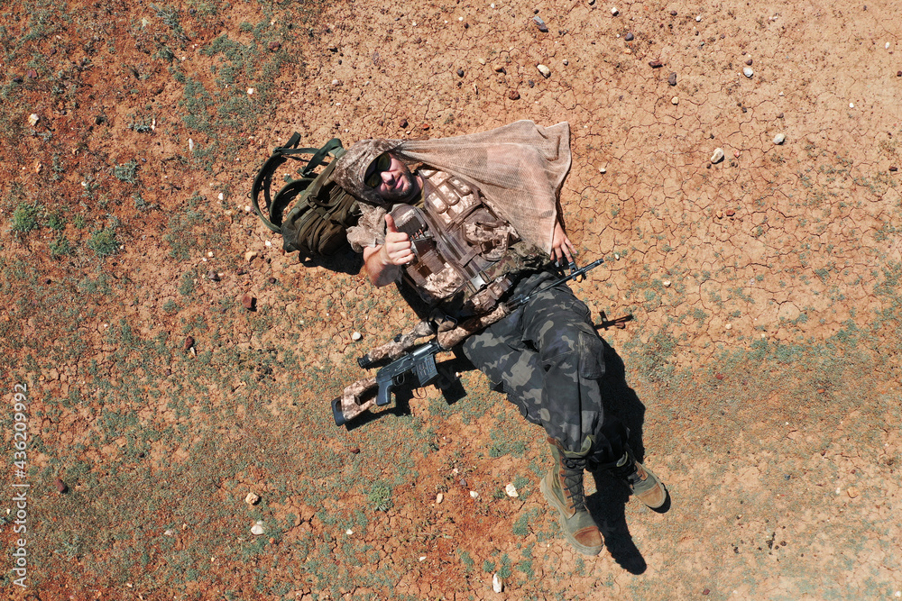 Top view - a soldier sniper while resting. He lies on the red-hot ...