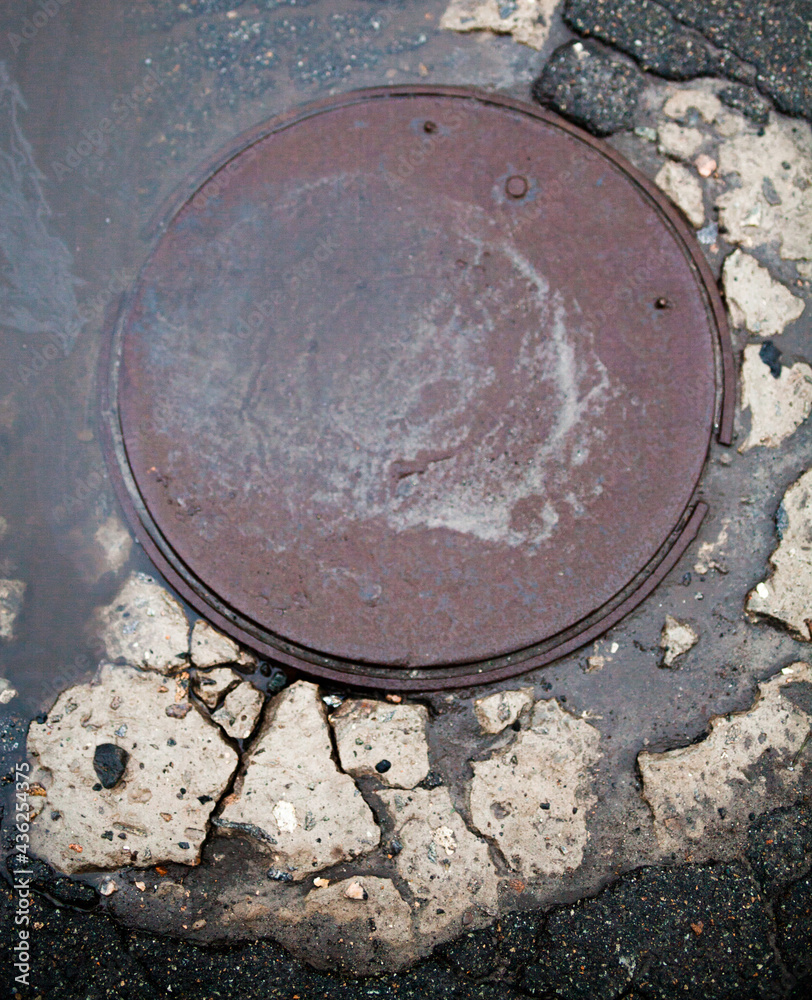 Manhole. The puddle on the manhole. Stock Photo | Adobe Stock