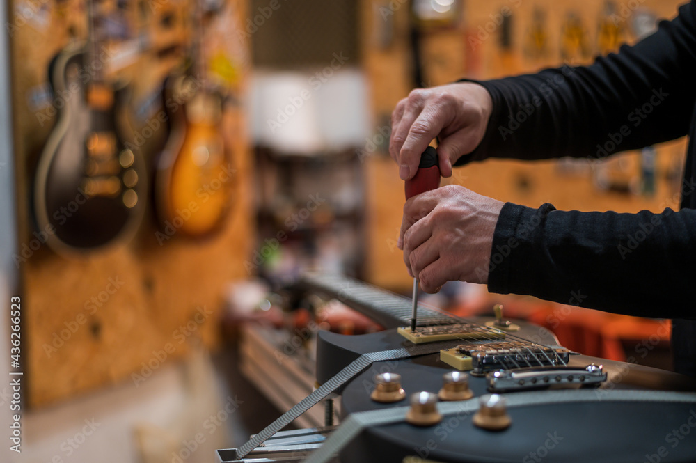 Black electrical guitar in repair service shop with a hands of a guitar ...