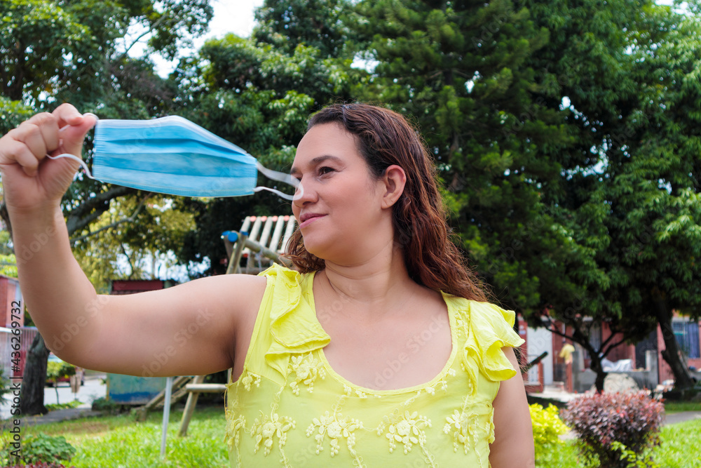 Alegre mujer latina quitándose el tapabocas por el fin de la pandemia ...