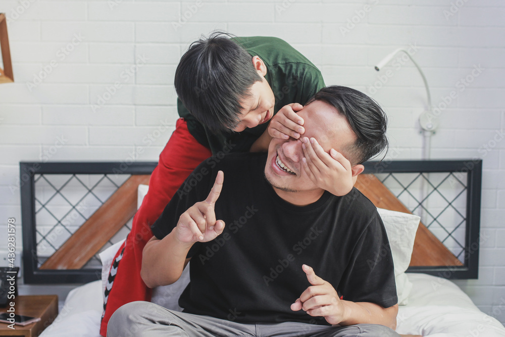 Boy playing with his father by closing his father eyes to make surprise ...