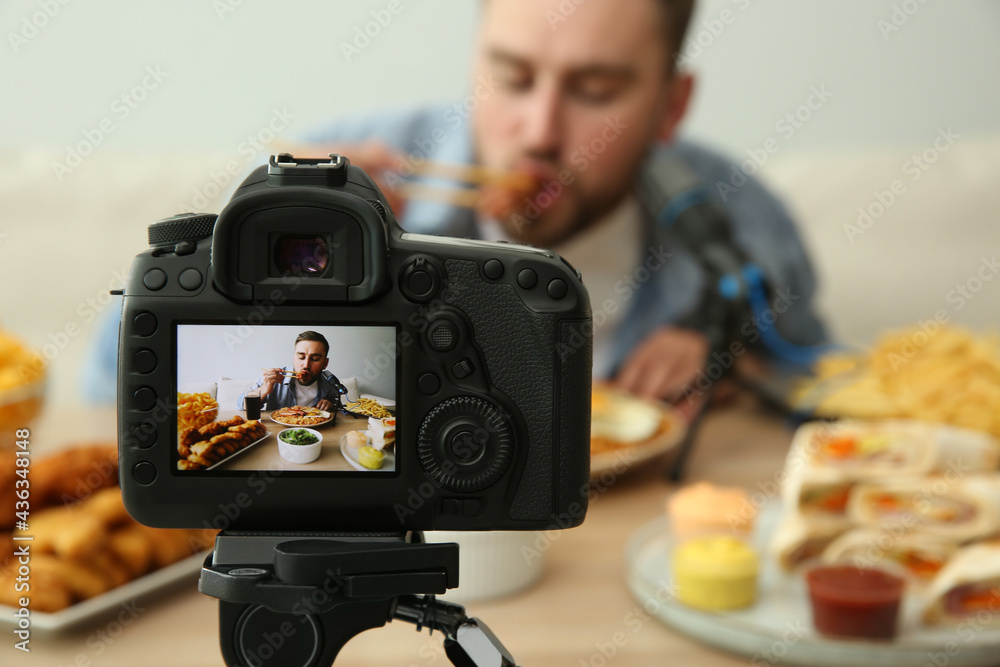 Food blogger recording eating show against light background, focus on ...
