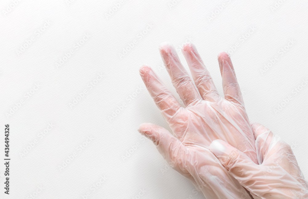 Two hands in transparent disposable vinyl gloves above white background ...